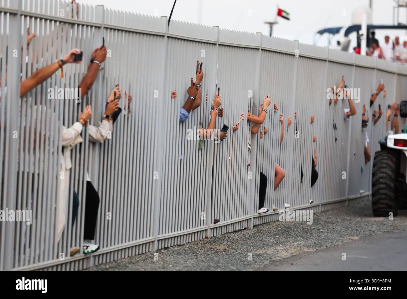 spectators, fans taking pictures with their phones through the fence ...