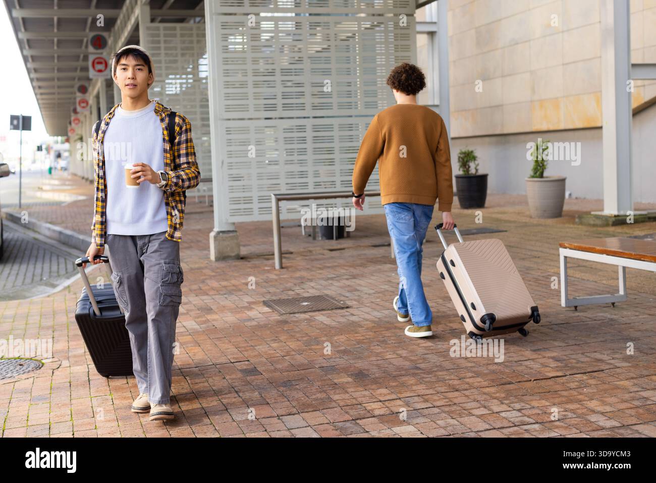 Diverse male travelers walking walkway holding coffee cup pulling ...