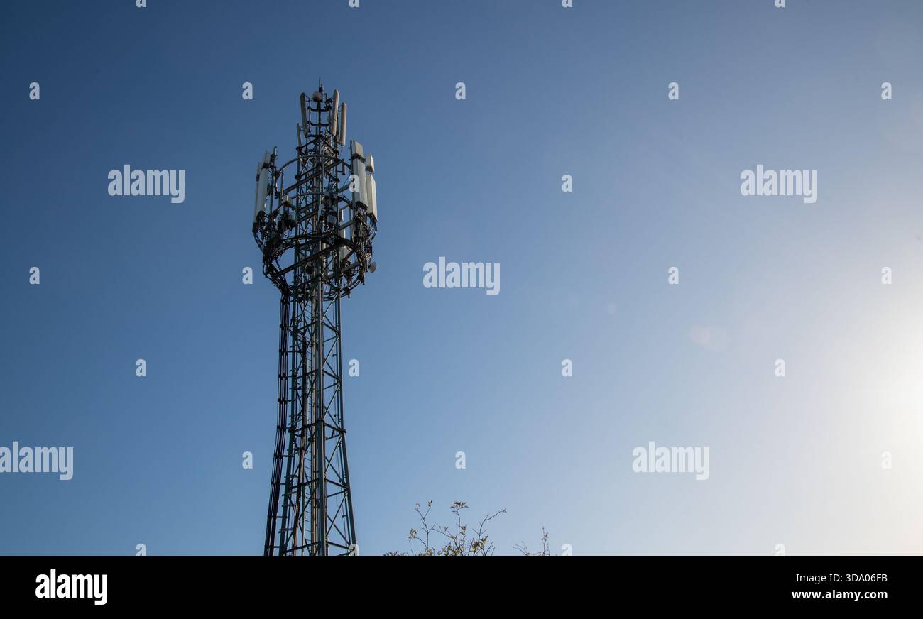 A tall mobile phone mast captured against a clear blue sky, showing ...