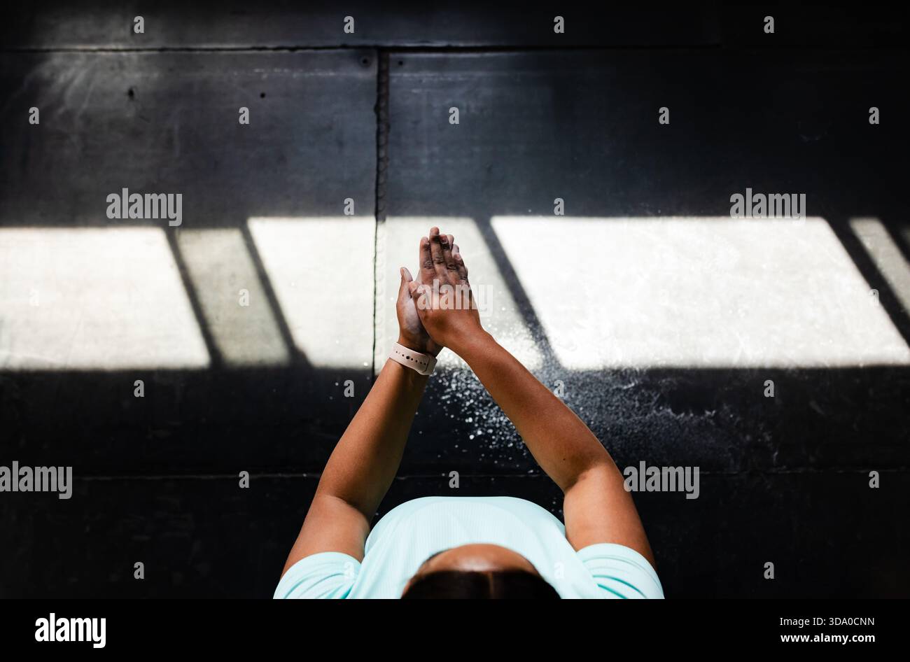 Athlete is raising arms and pressing hands, releasing chalk dust on gym ...