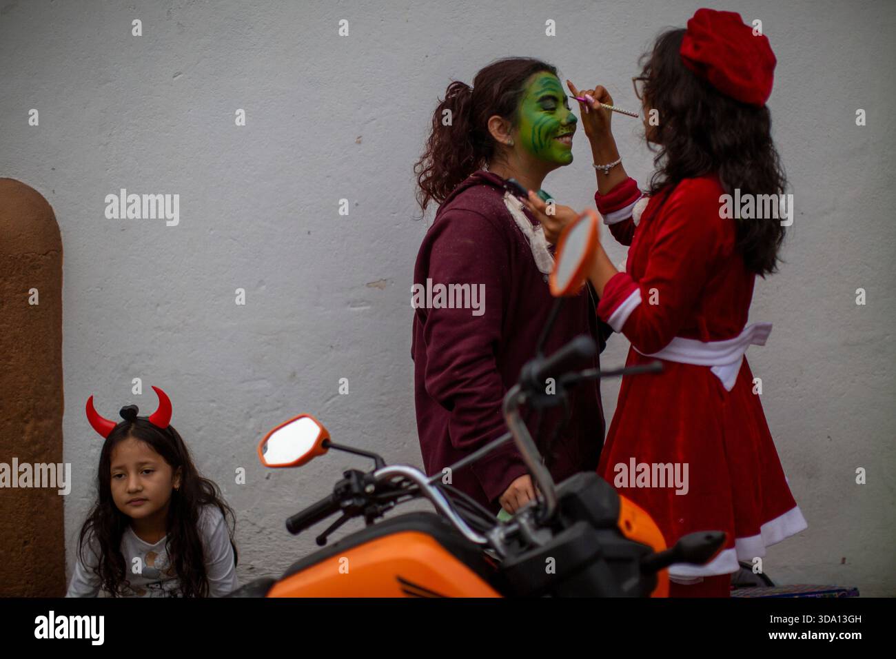 A woman is made up like the Grinch, and next to her sits a little girl ...