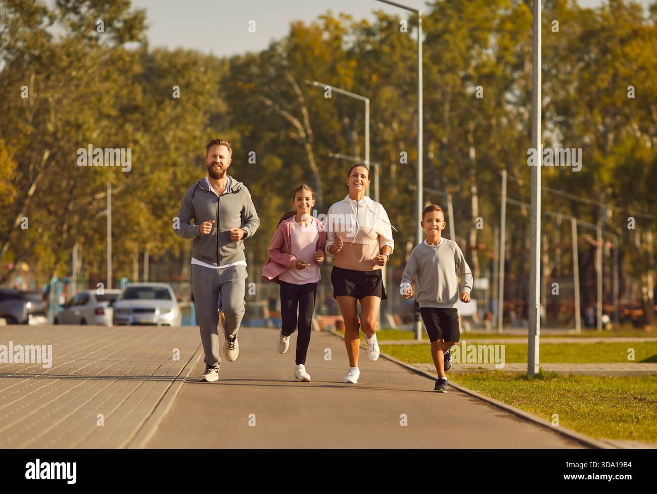 Parents and kids running together in city park, healthy family jogging ...