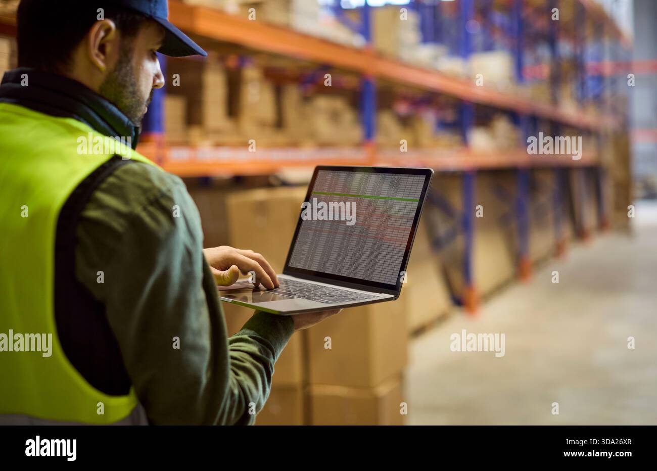 Warehouse worker with laptop auditing stock on shelves, inventory ...