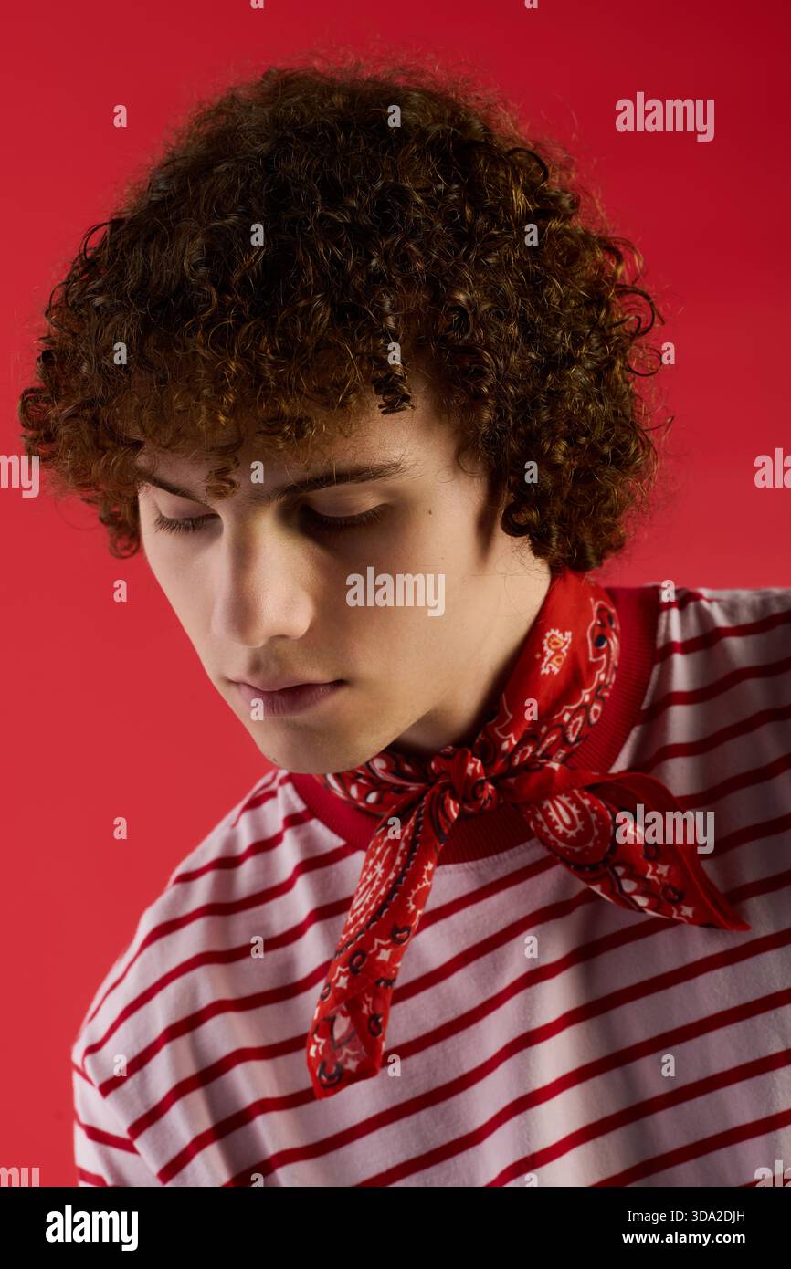 Teen boy in stylish clothes poses confidently against a bold red ...