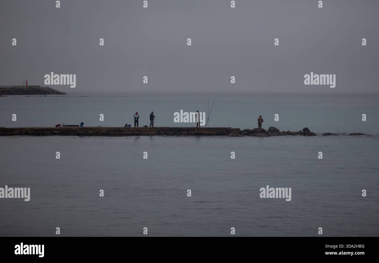 08 December 2025, Spain, Palma: People fishing on Can Pere Antoni beach ...