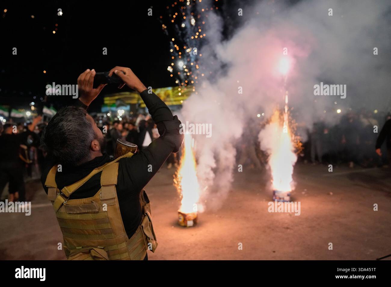A Syrian policeman takes pictures of the fireworks during celebrations ...