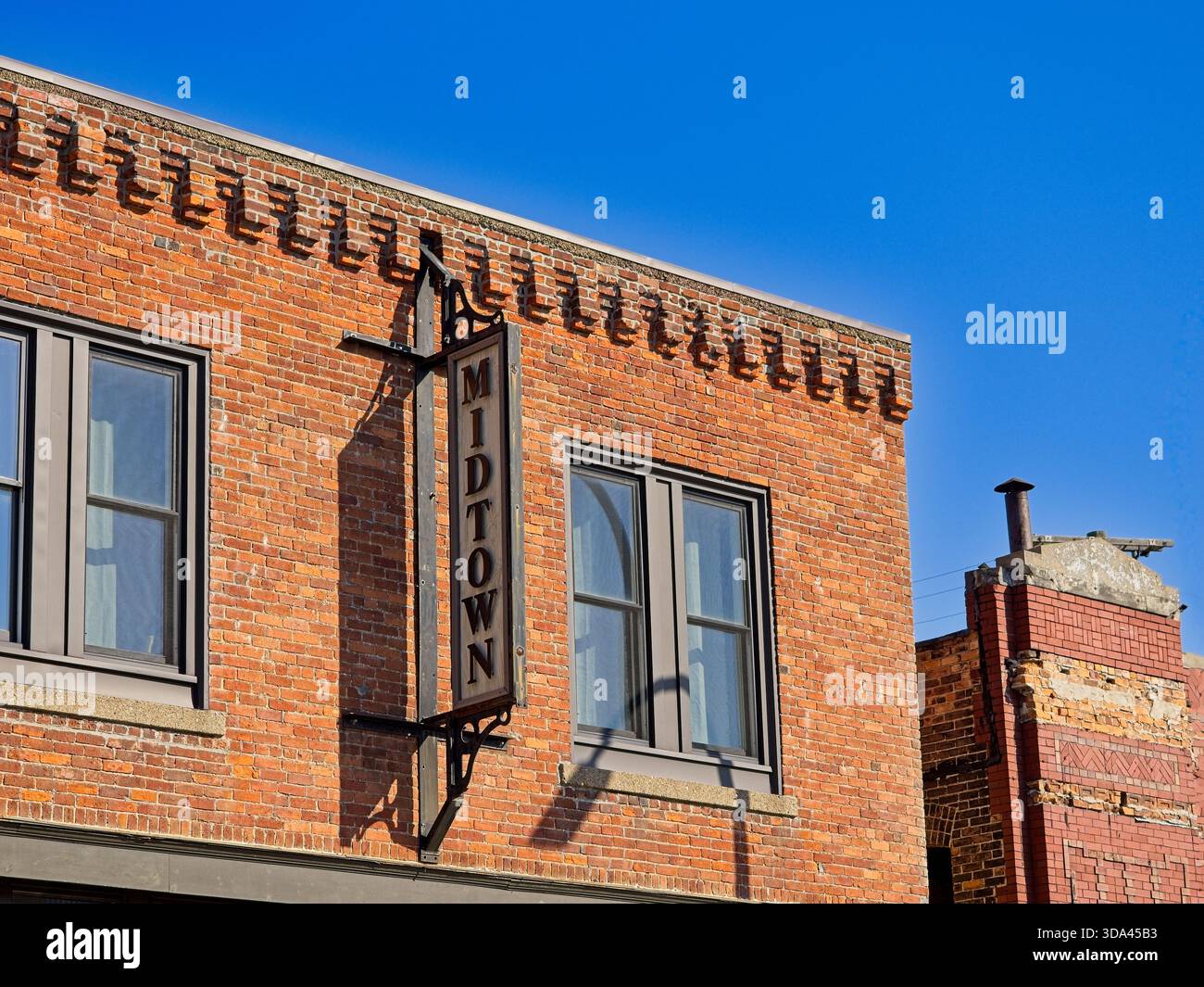 Projecting sign “Midtown” on old brick building with ornate cornice ...