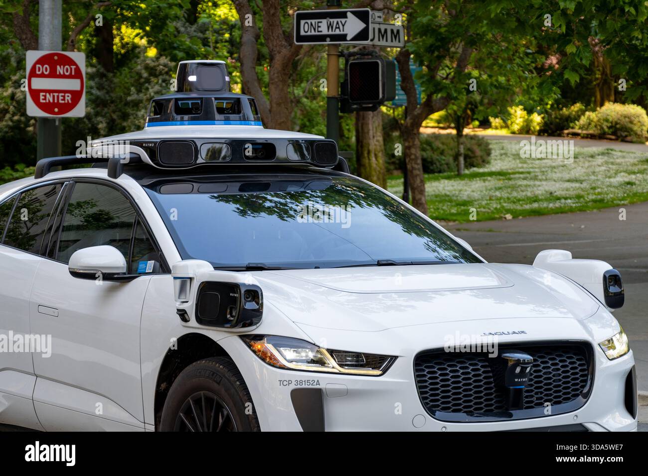 Waymo autonomous Jaguar I-Pace SUV equipped with rooftop lidar and cameras navigating ...