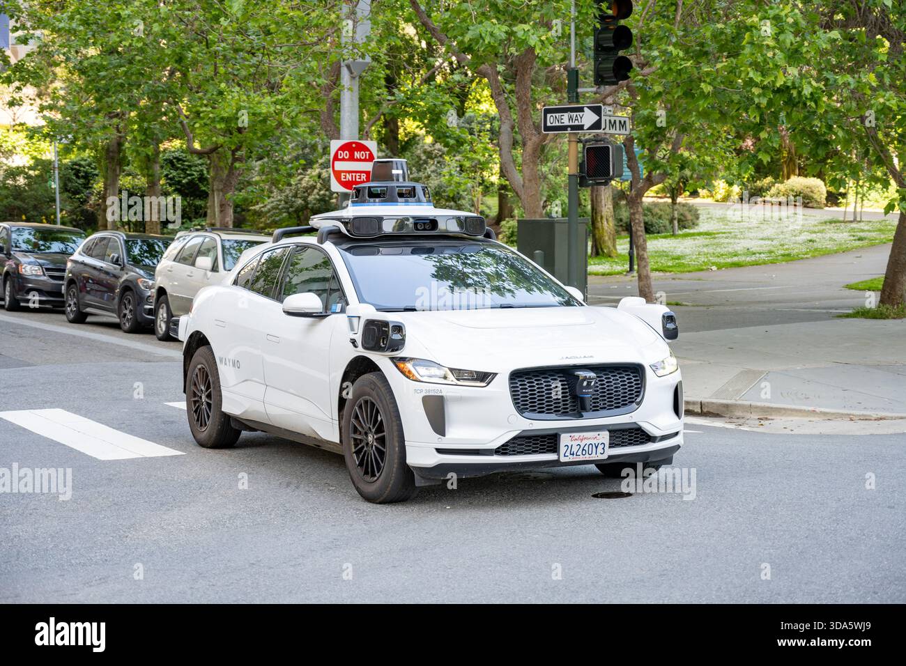 Waymo autonomous Jaguar I-Pace SUV equipped with rooftop lidar and cameras navigating ...