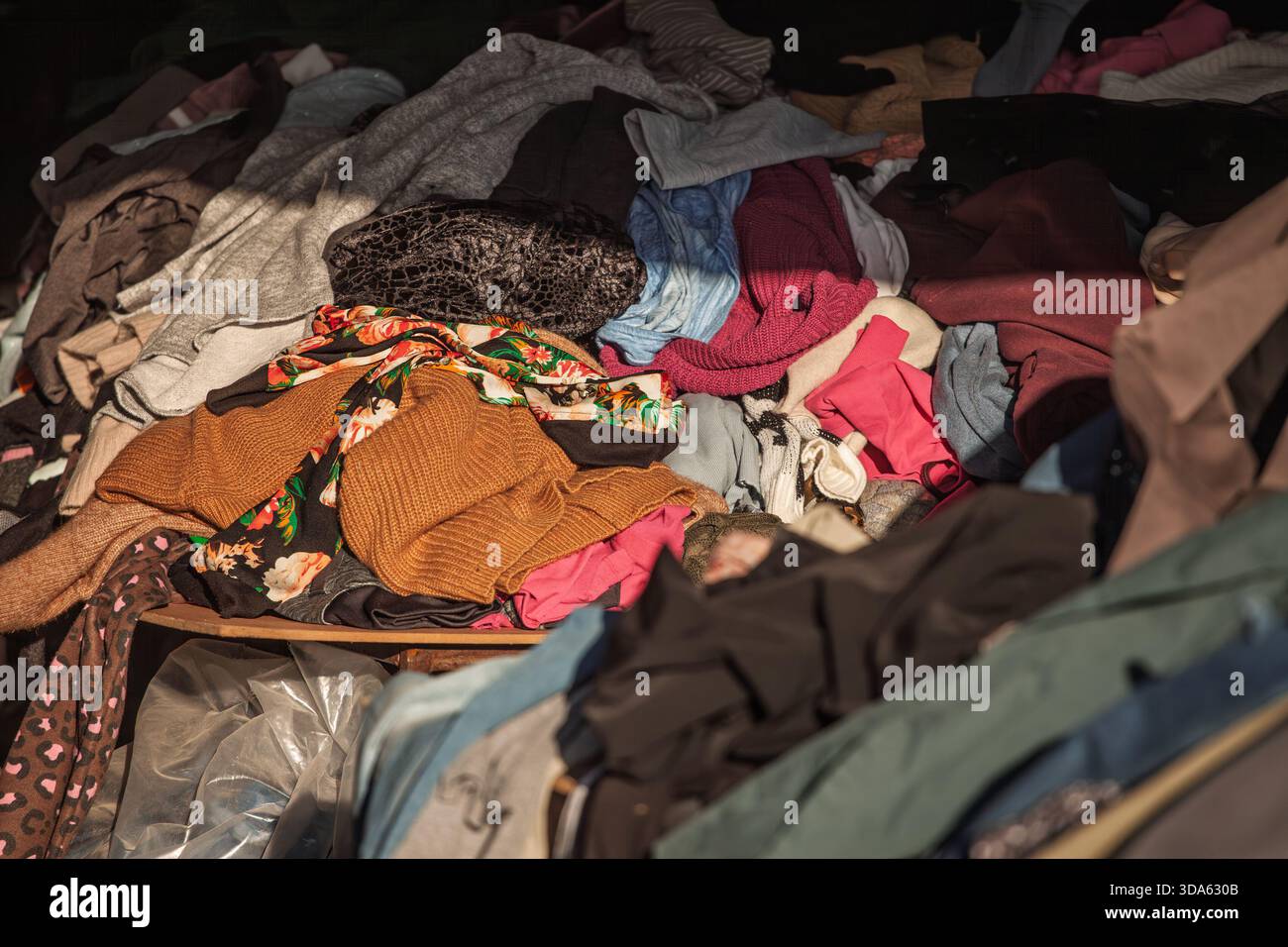 Piles of second hand clothes in a flea market, with mixed garments and ...