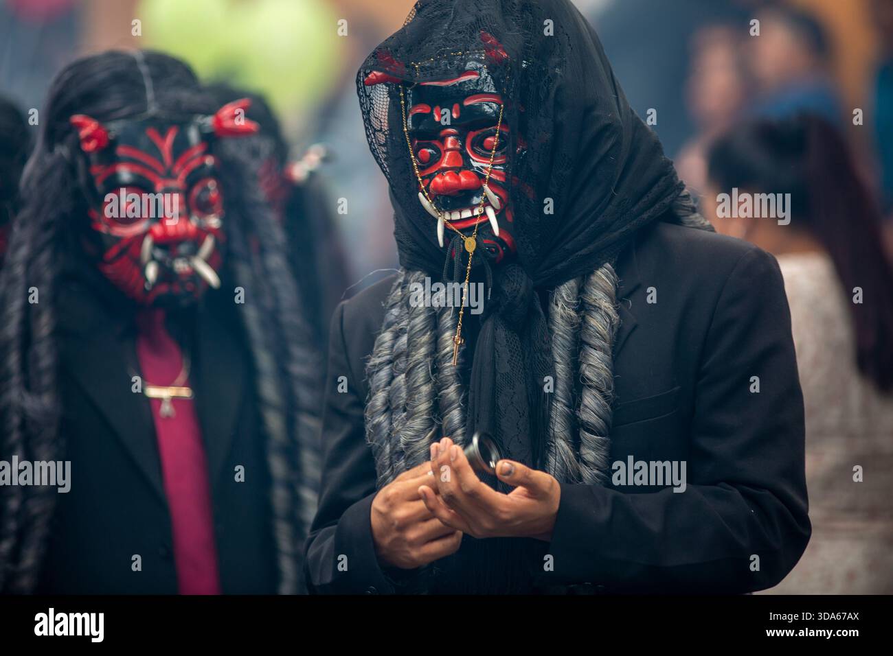 A man dressed as a devil dances while ringing a bell during the ...