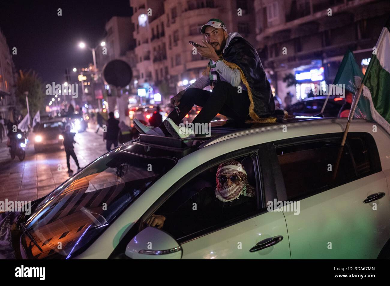 A person sits on top of a car during celebrations in the streets of the ...
