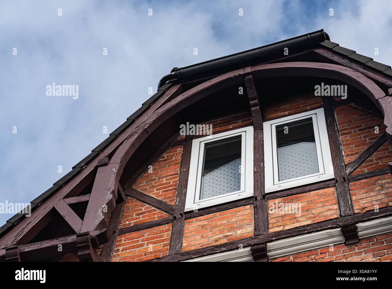 The upper part of a building shows a gable roof with wooden framing ...