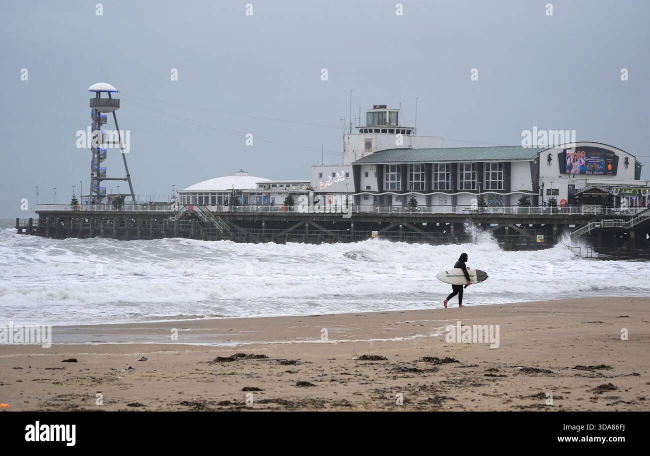 A surfer makes their way out of the sea on Bournemouth beach in Dorset ...