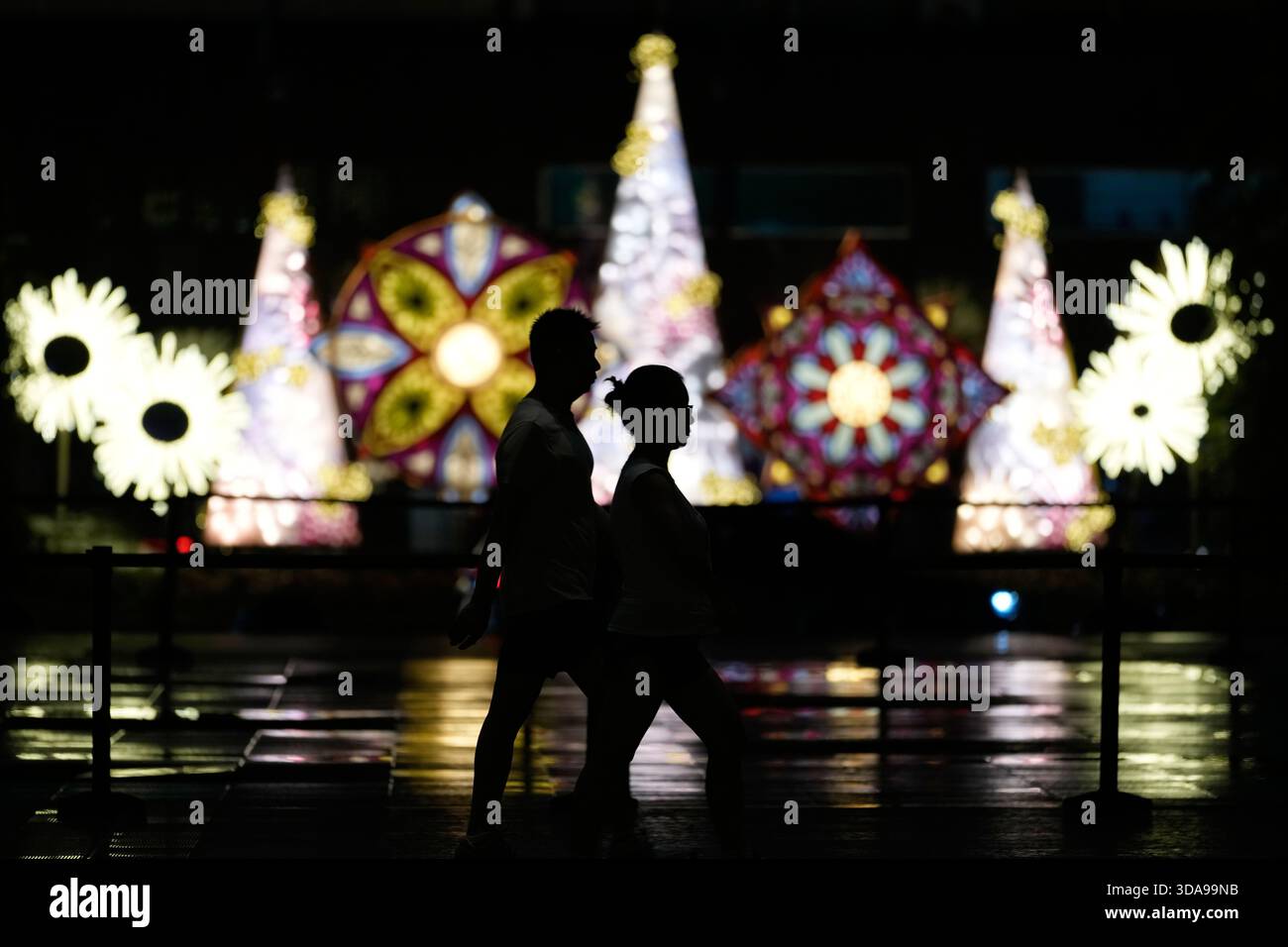 People walk past a holiday lights display in Makati, Philippines ...