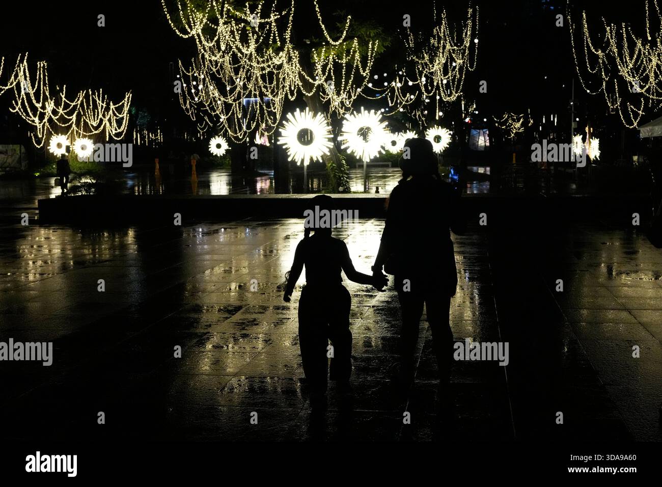 People look at a holiday lights display in Makati, Philippines, Tuesday ...