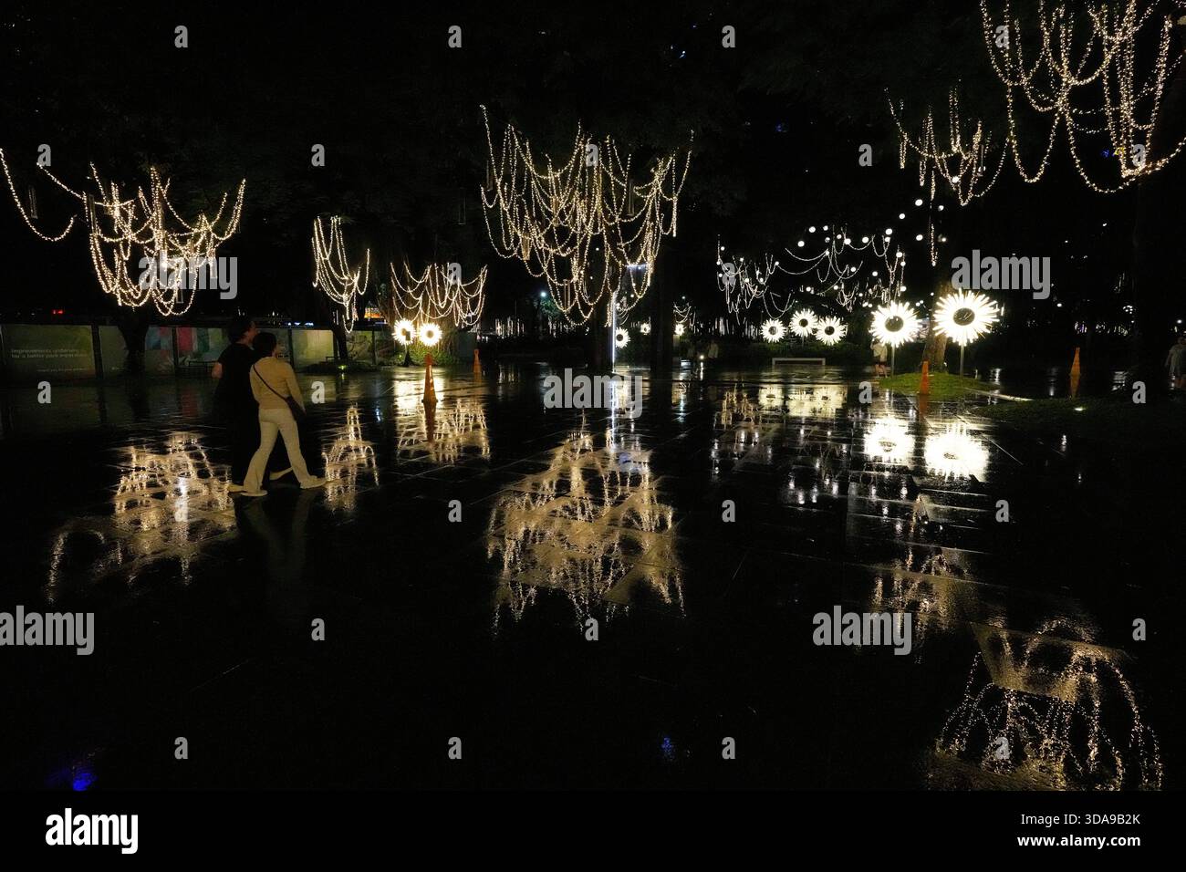 Holiday lights are reflected in a rain-soaked plaza in Makati ...