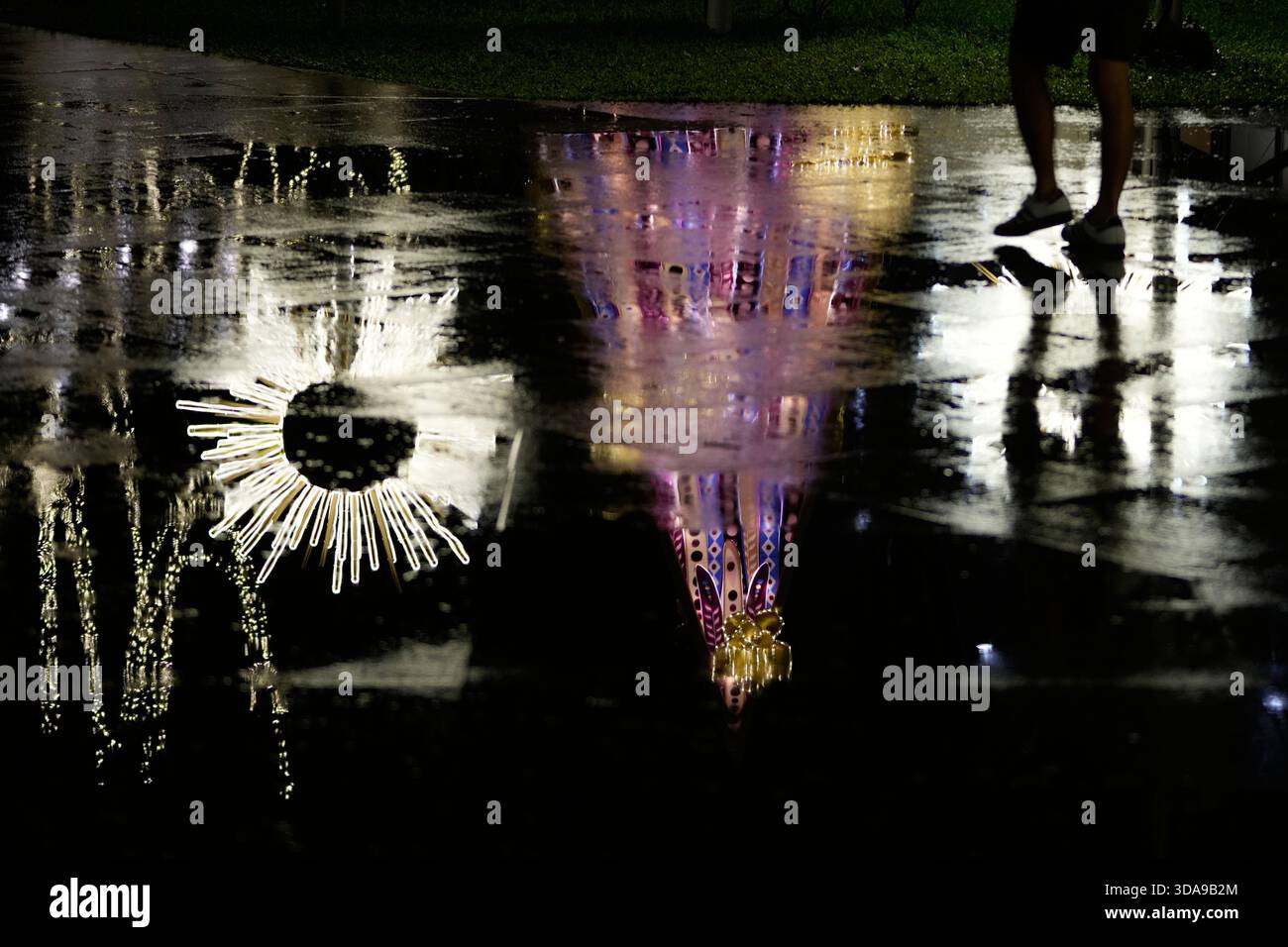 Holiday lights are reflected in a rain-soaked plaza in Makati ...