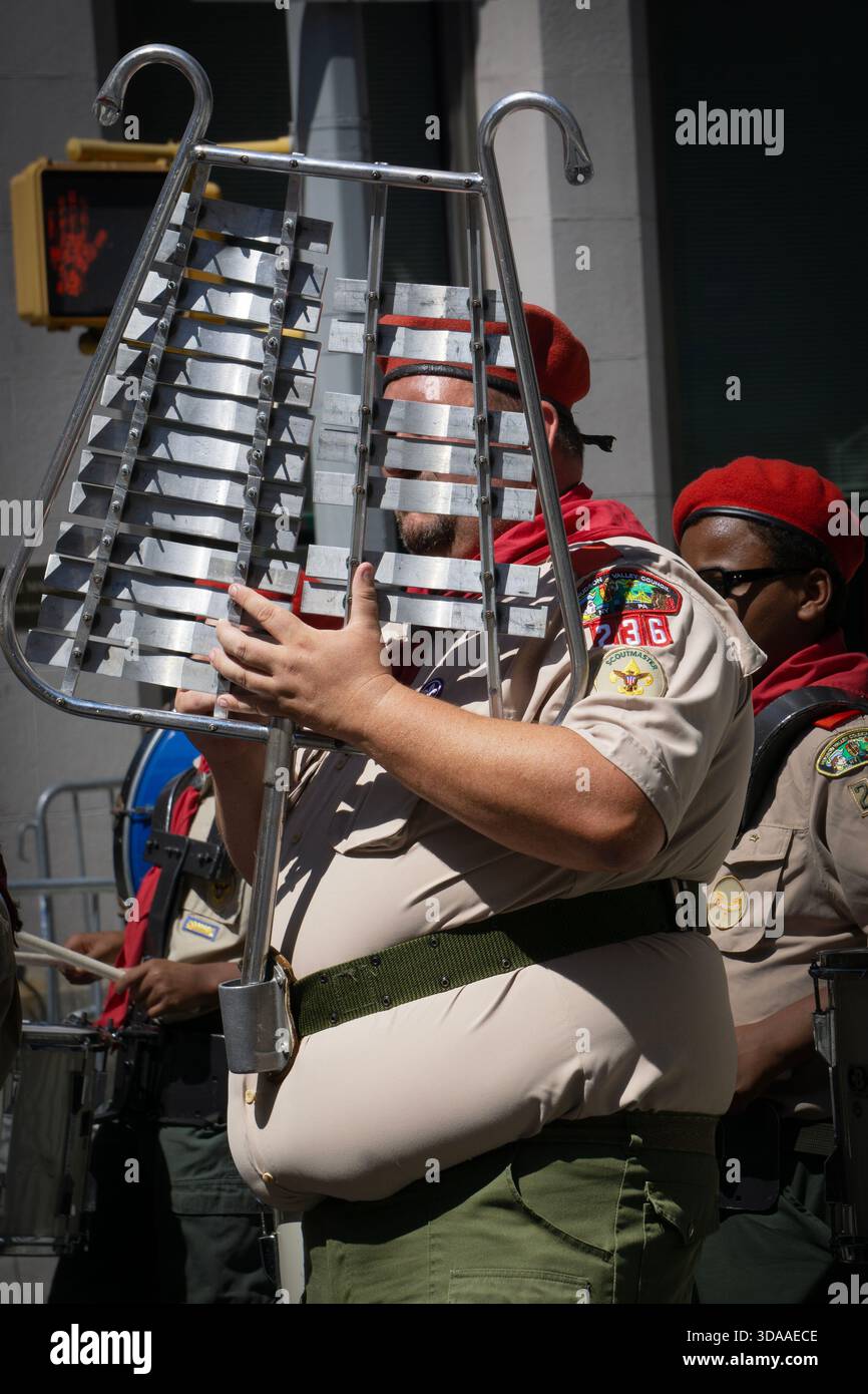 An anonymous glockenspiel player marches with a cub scout troupe at a ...