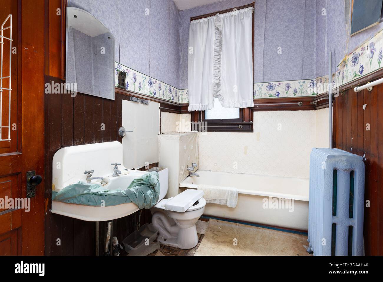 An old bathroom interior with purple floral wallpaper, a worn sink ...