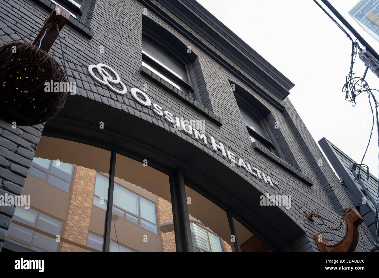 Low-angle view of Ossium Health sign on dark brick building facade in ...
