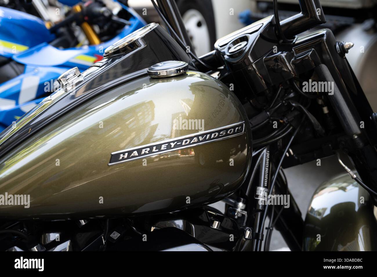 Close-up of olive green Harley-Davidson motorcycle fuel tank with urban ...