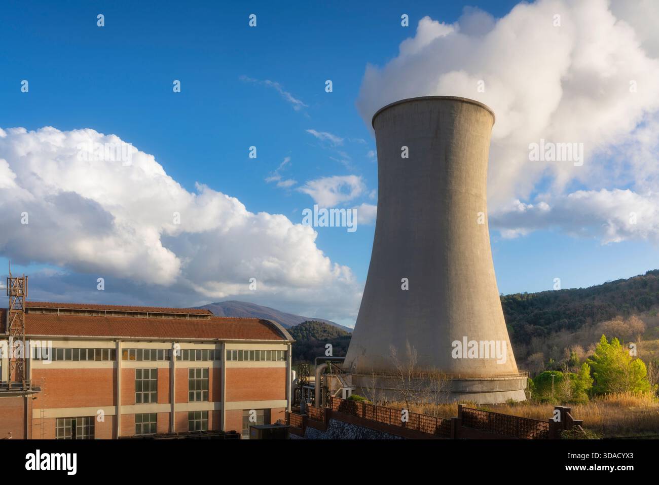 View of a large concrete cooling tower releasing white steam in the ...