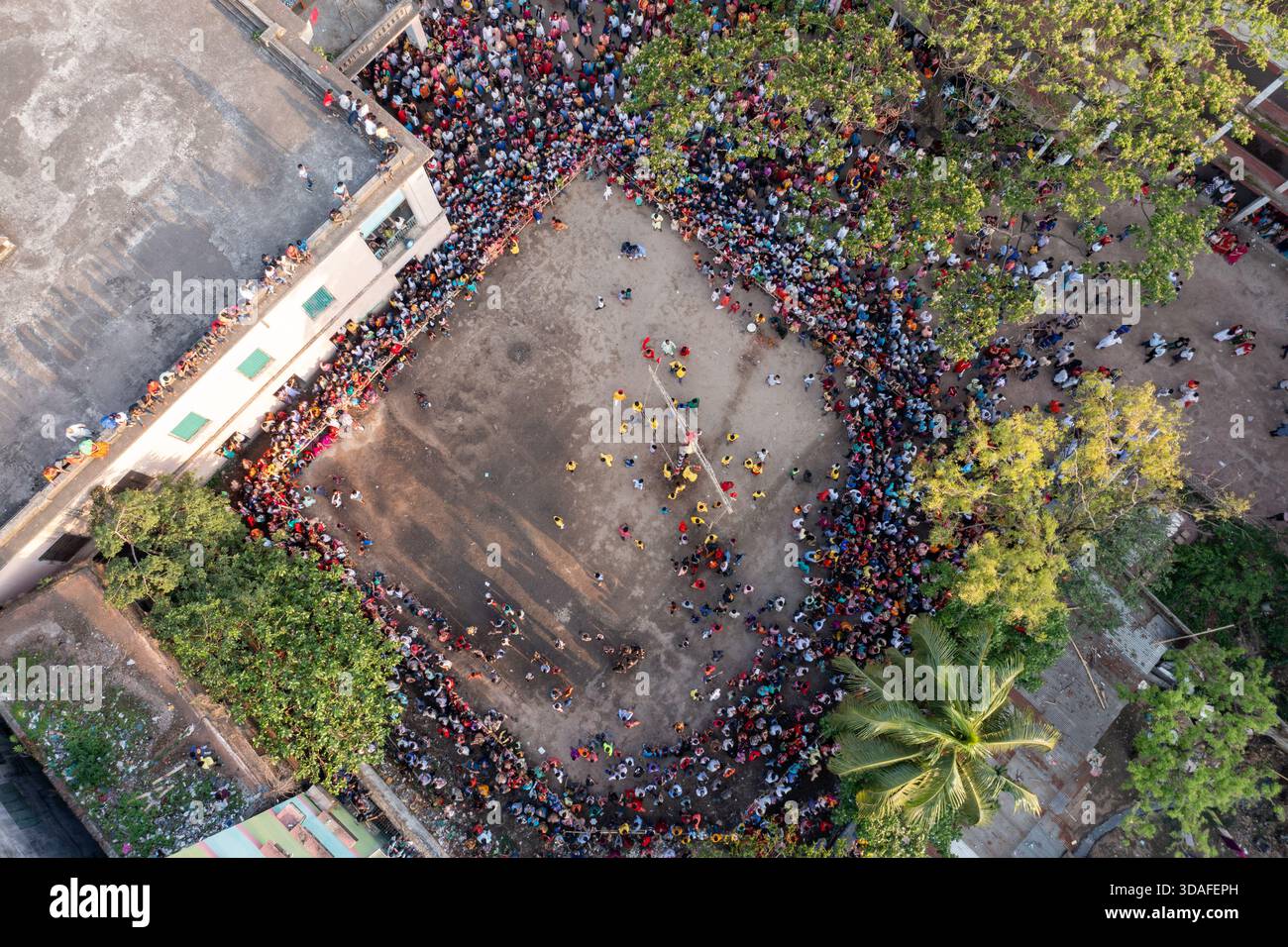 Aerial view of a vibrant crowd gathers in a square outlined by trees ...