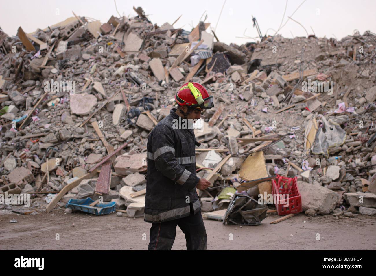 A rescue worker walks next to the wreckage of two collapsed buildings ...