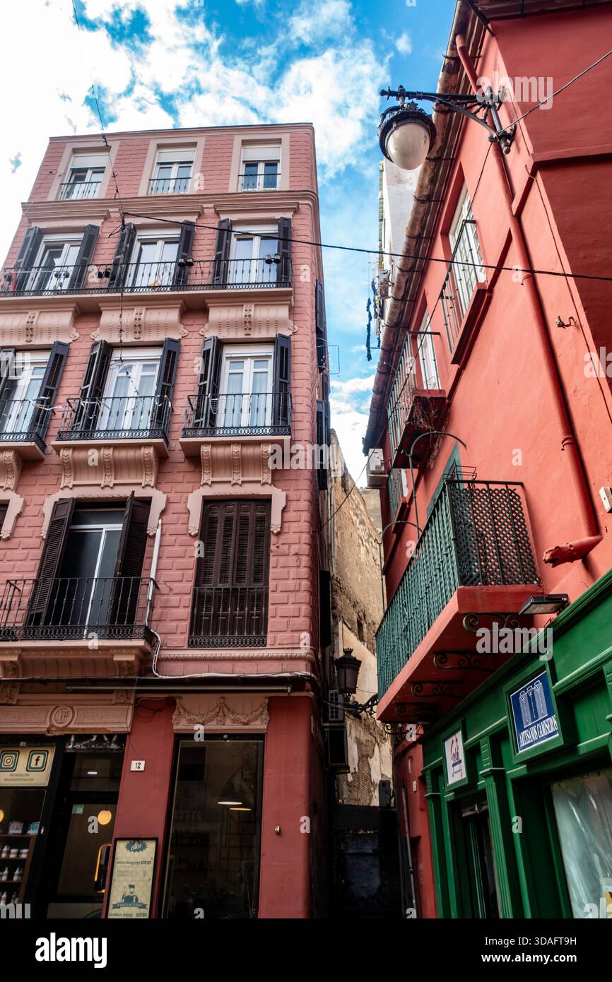 Narrow street view between tall, traditional buildings in Malaga, Spain ...