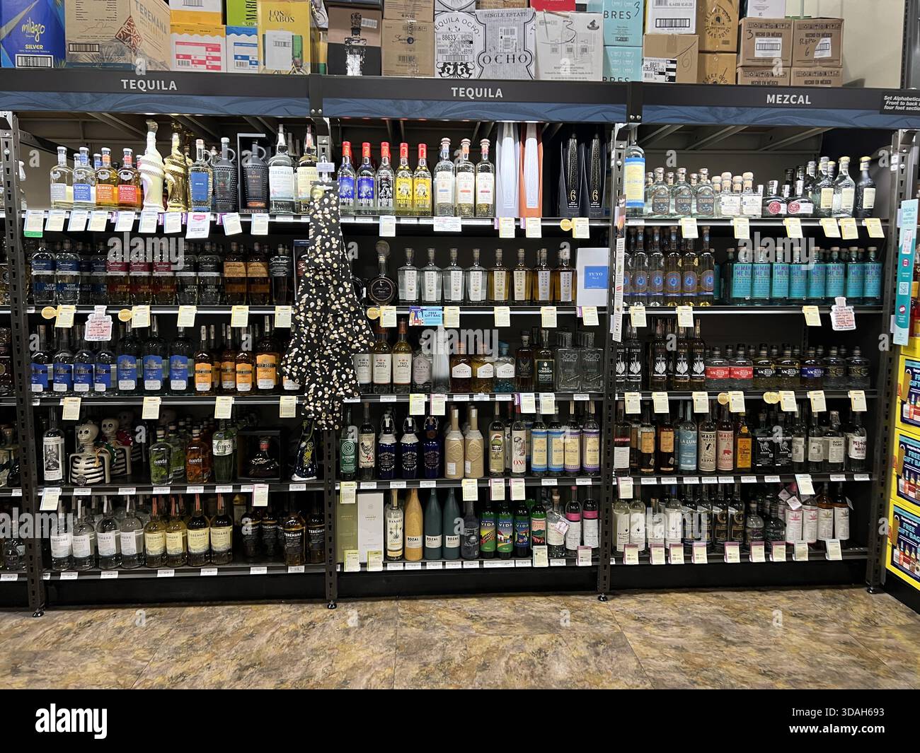 Shelves stocked with a variety of tequila and mezcal bottles on display ...