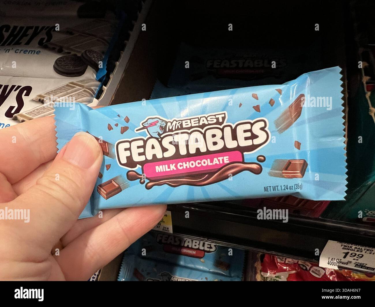 Person's hand holding a Mr Beast Feastables brand chocolate bar, Walnut ...