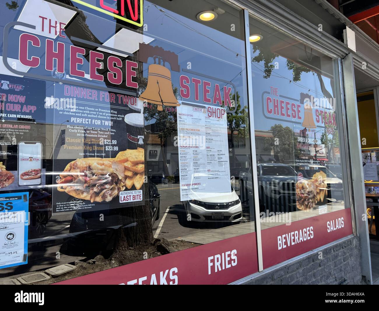 Front windows of The Cheese Steak Shop displaying menu and promotional ...