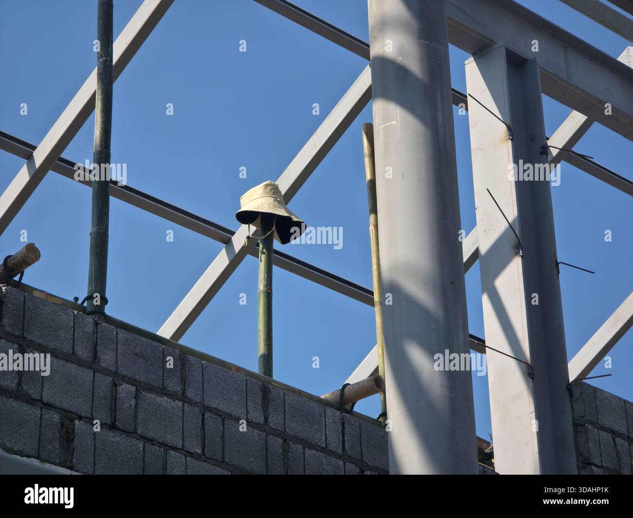 Yellow hard hat rests on pole at quiet construction site. This ...