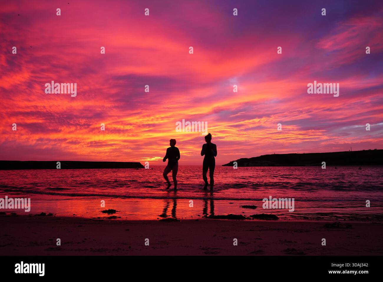 People enter the North Sea as the sun rises over Cullercoats Bay in ...