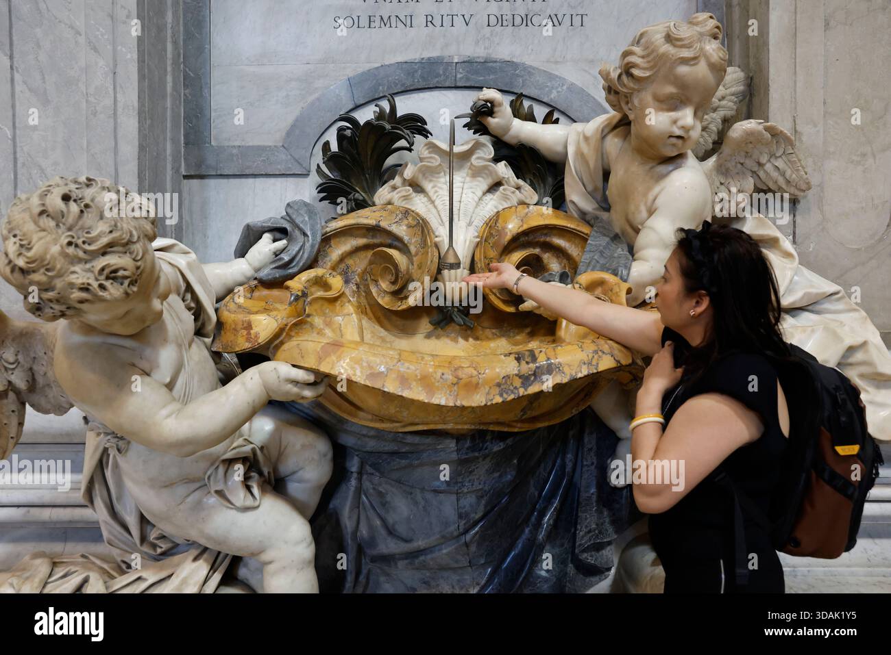 St. Peter’s Basilica. Visitor reaches toward ornate marble stoup ...