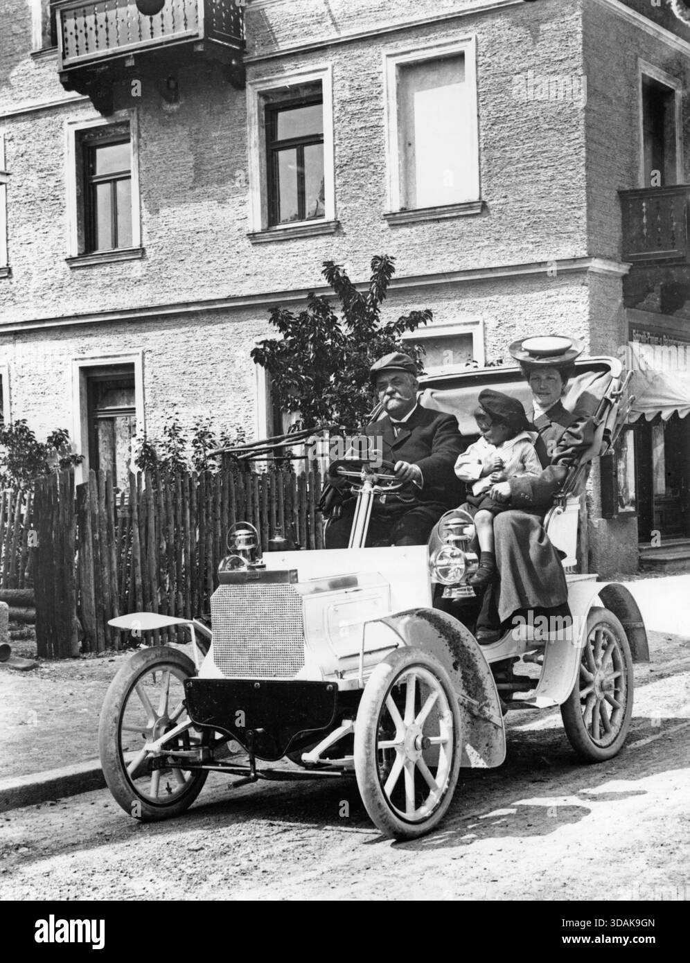 The picture shows a family with a child in an early automobile from ...