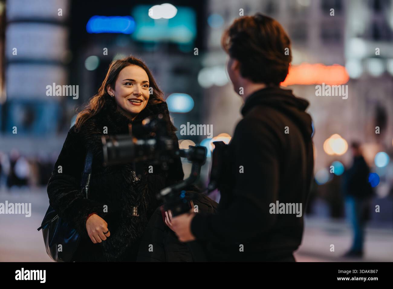 Two friends talk at night on a city street as a camera captures their ...