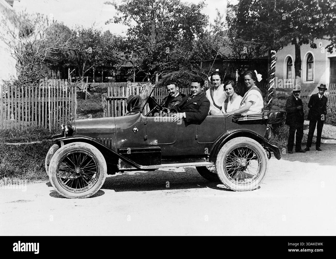 A group of day-trippers take a ride in a car. There are two men in the ...