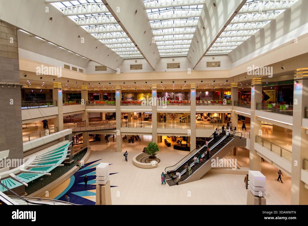 View of a multi-level shopping mall interior with an escalator, stores ...