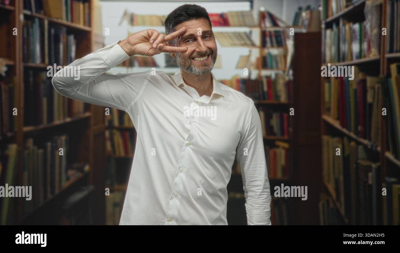 Man with beard and white shirt smiles and shows peace sign while ...
