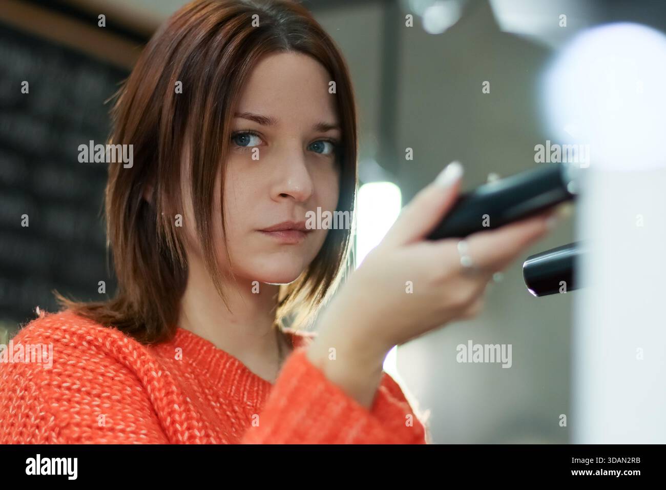 Side angle of woman with short hair in knitwear securing portafilter on ...