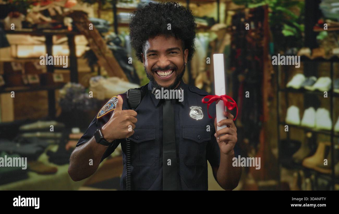 African american police officer smiling with thumbs up and diploma in a ...