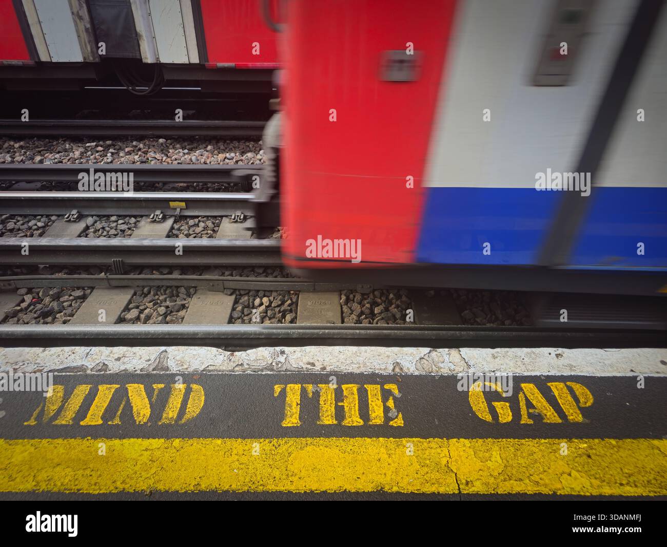 Yellow mind the gap text on a london subway platform with approaching ...