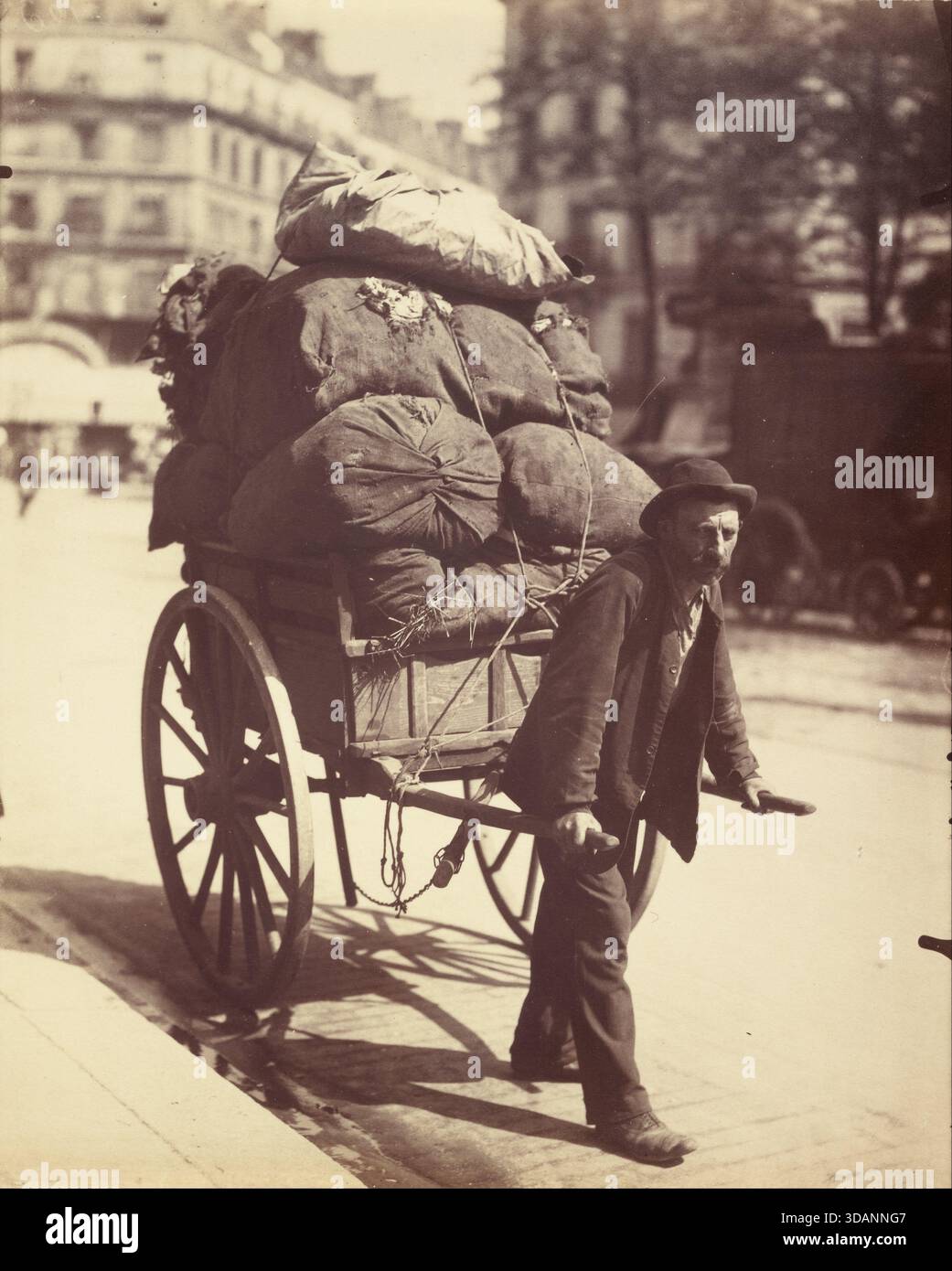 Chiffonier (Ragpicker) . Man pulling cart with old fabric and rags he ...