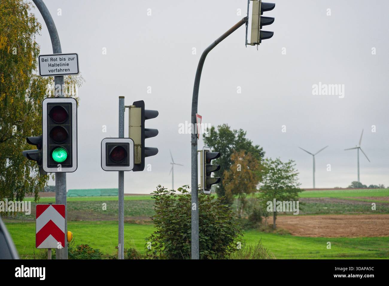 Three metal poles stand along the roadway and each holds two signal ...
