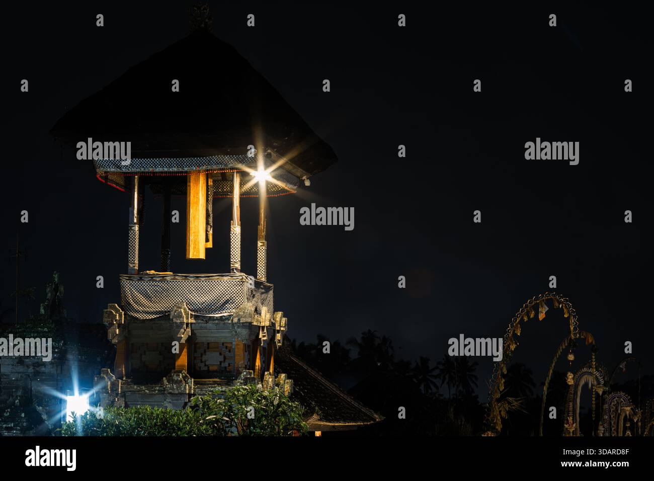 A traditional Balinese kulkul tower glowing at night in Penglipuran ...