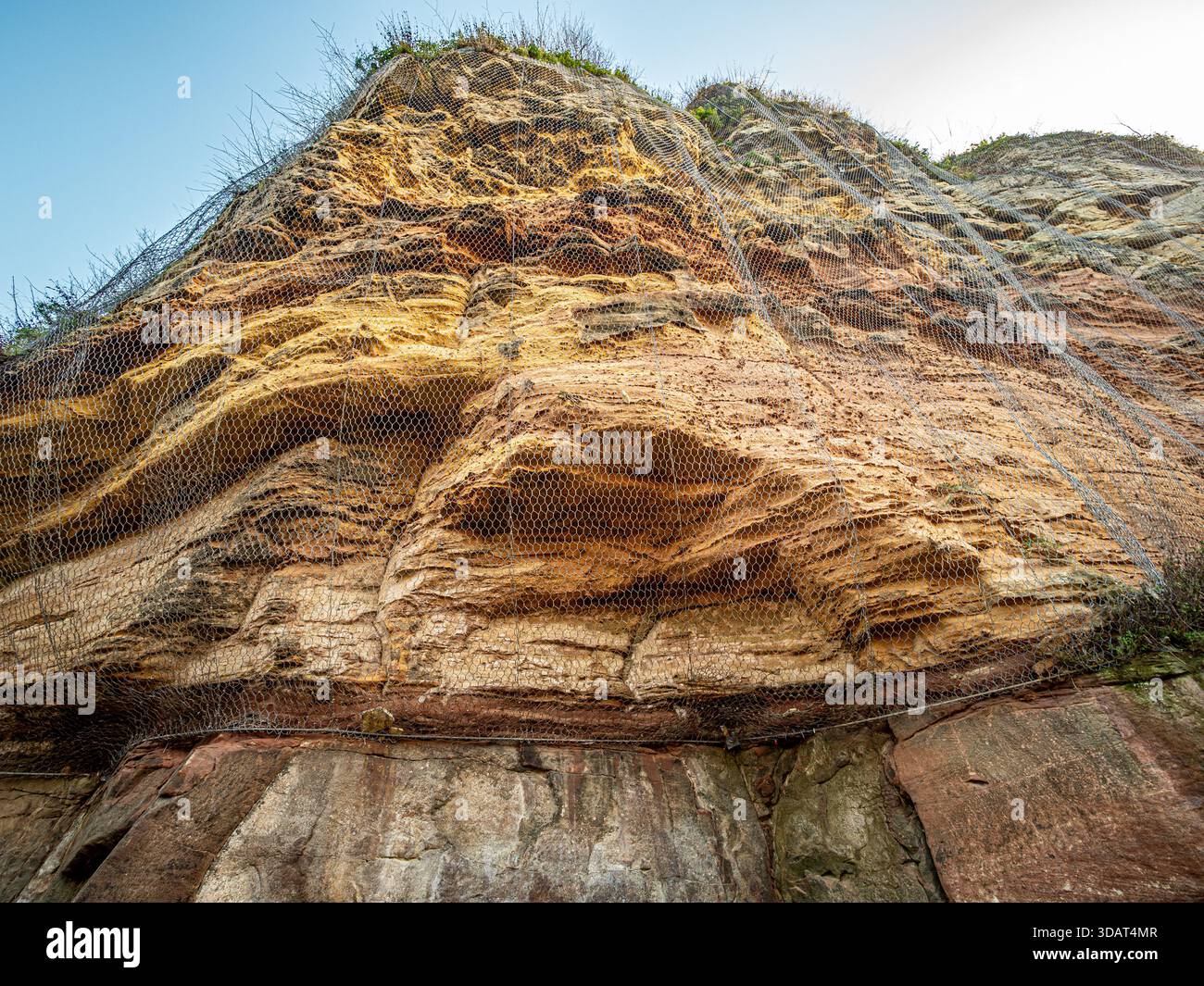 Safety netting covering the textured sandstone cliff face below the ...