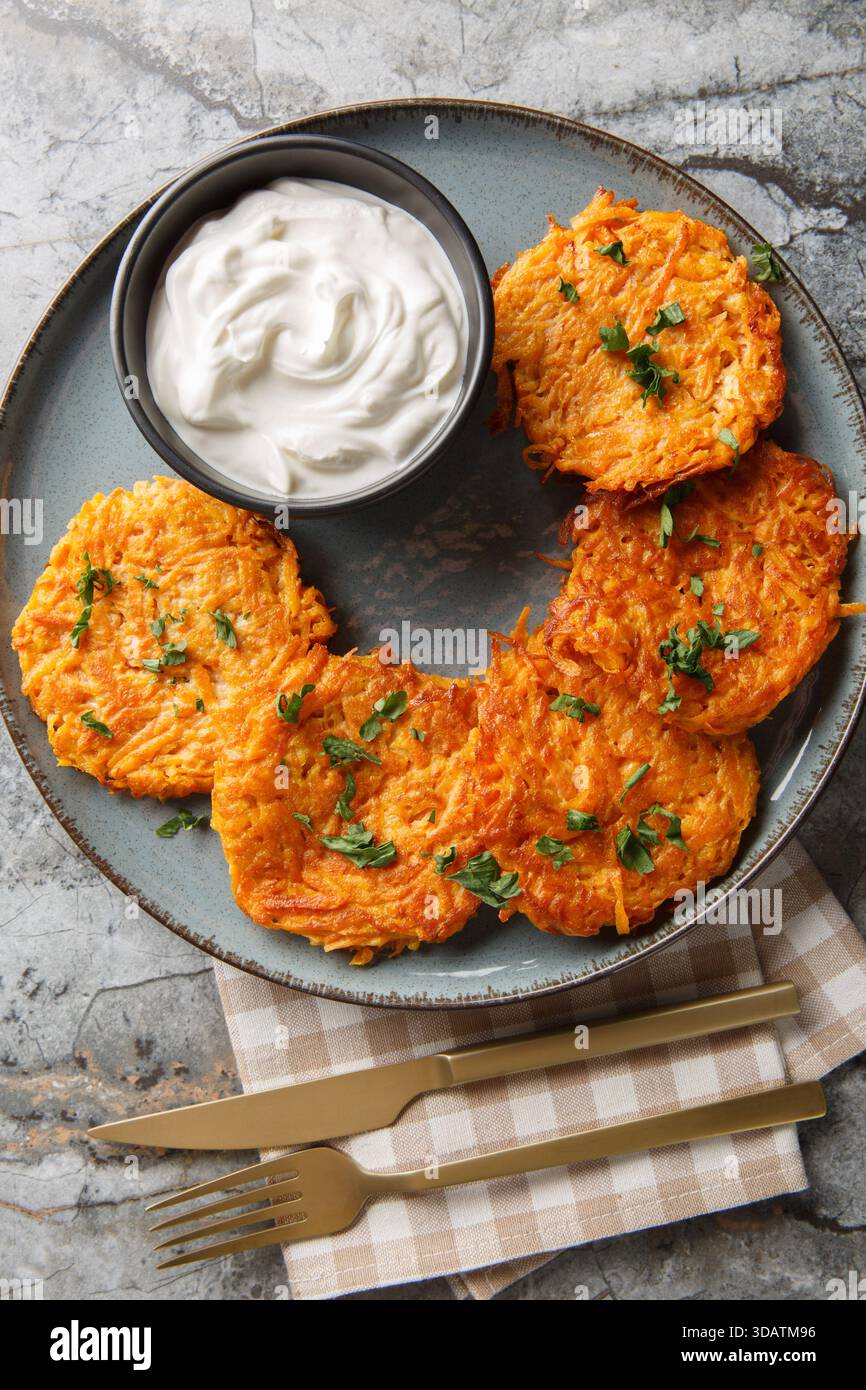 Sweet Potato Hash Browns served with sour cream closeup on the plate on ...
