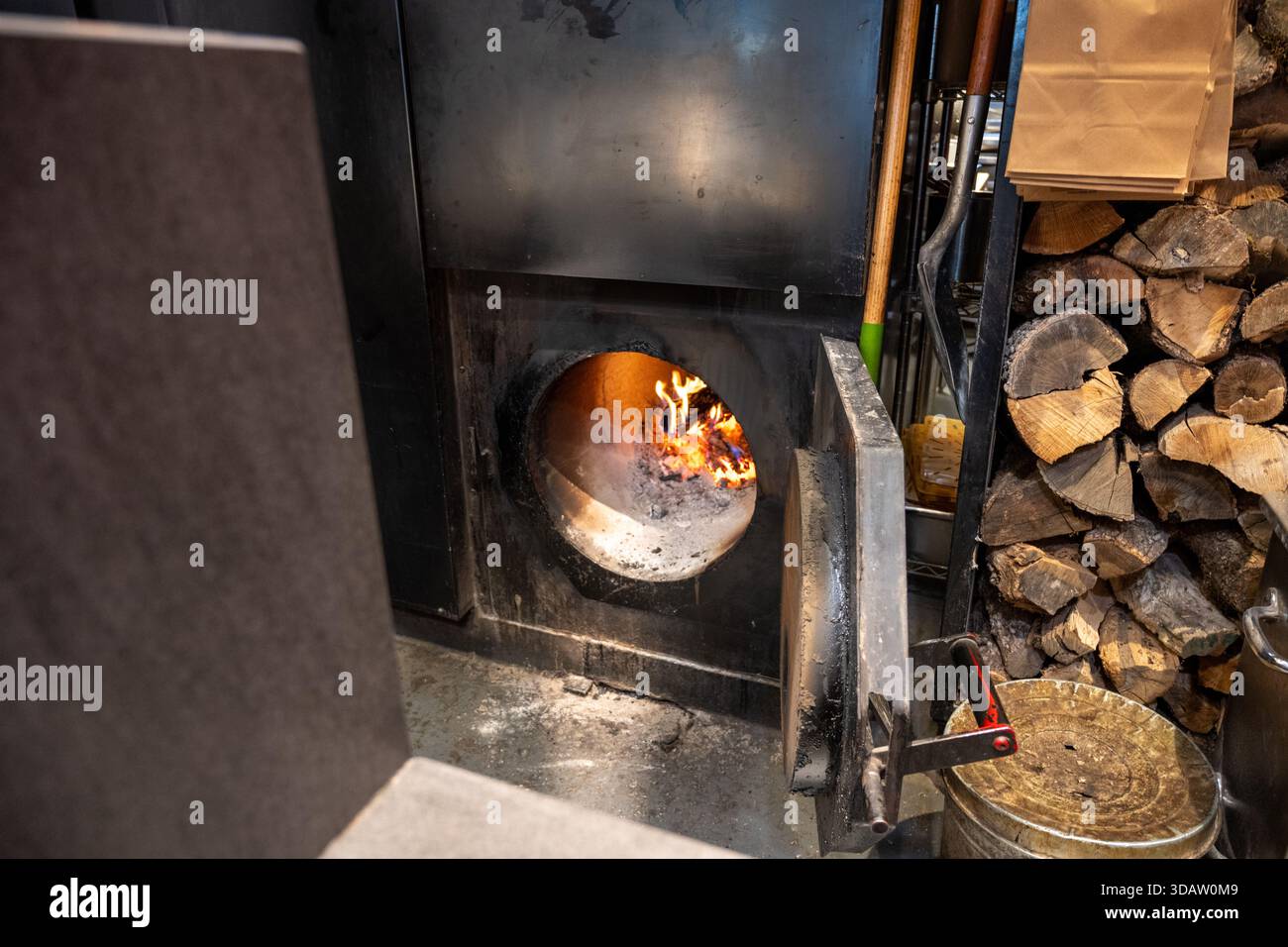 A door is open, showing fire inside a wood fired barbecue pit for ...